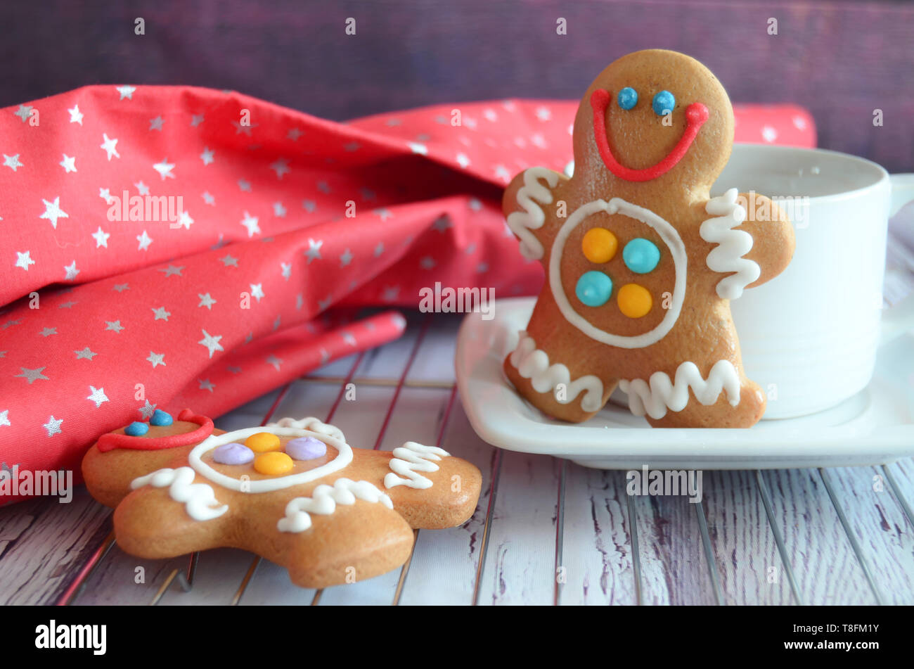 White cup of tea with a gingerbread man cookie, another gingerbread man ...