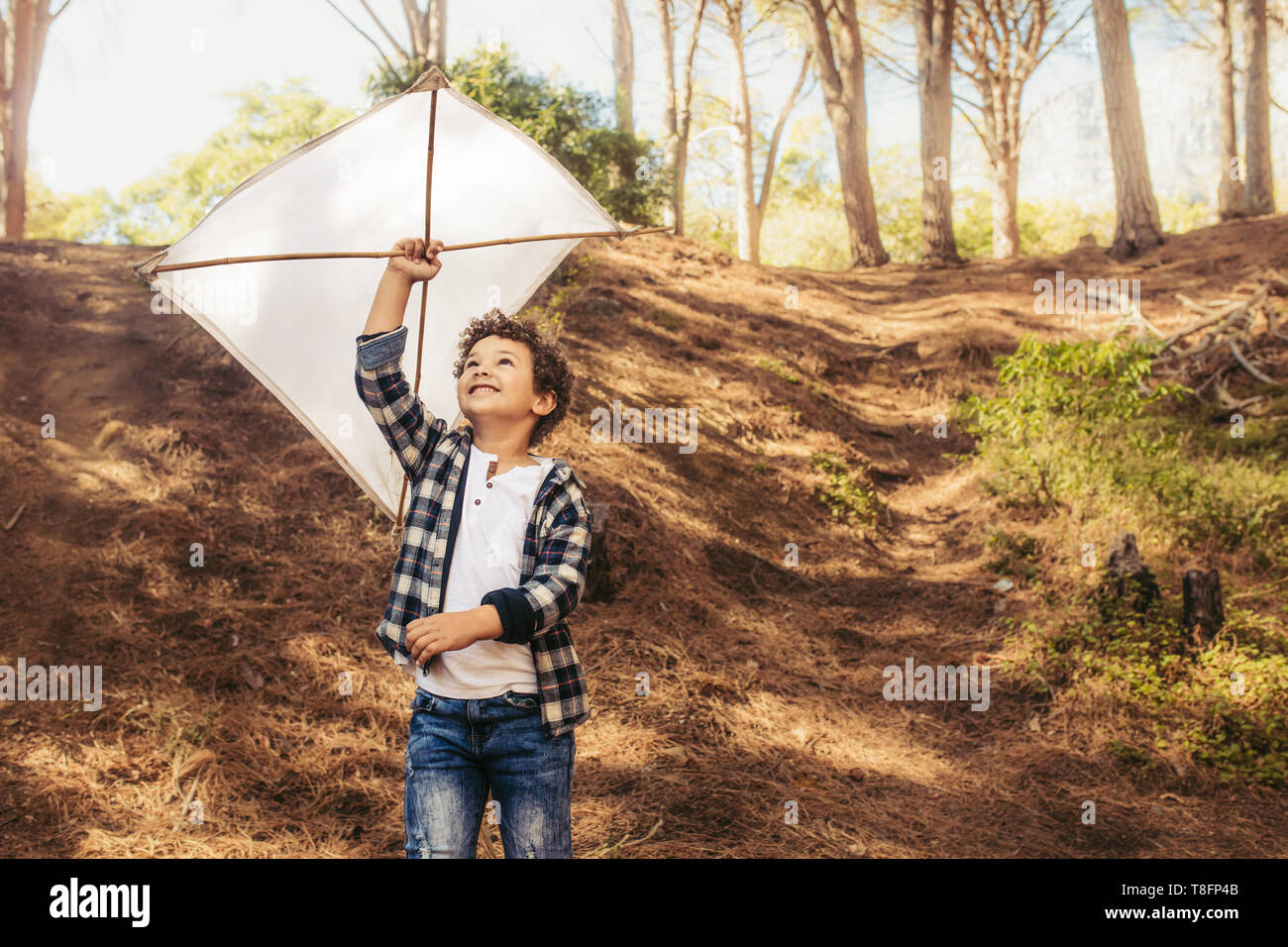 Cute boy flying a kite. Child playing with a handmade kite in forest ...