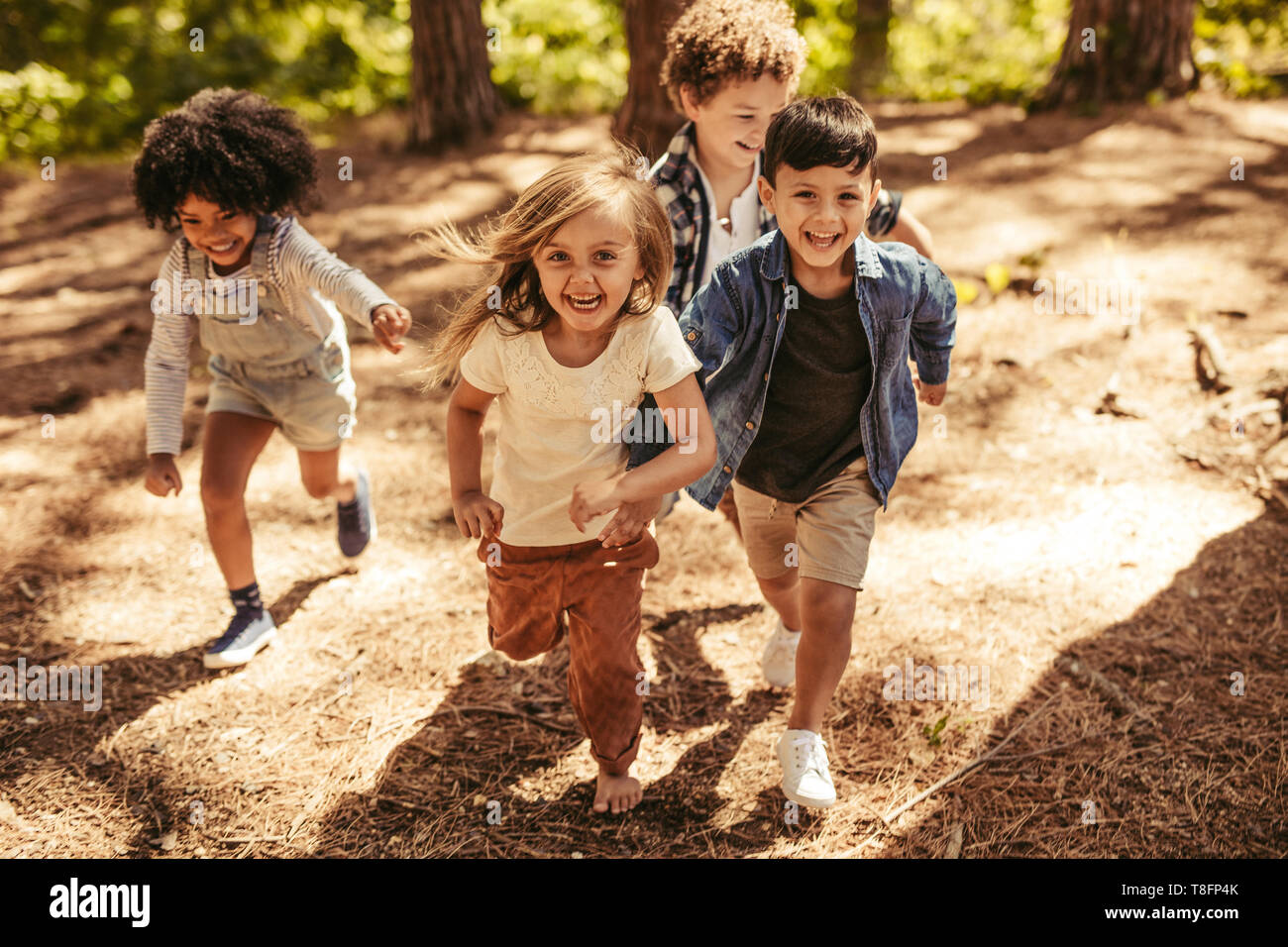 Group of four kids running together in the forest. Children having a ...