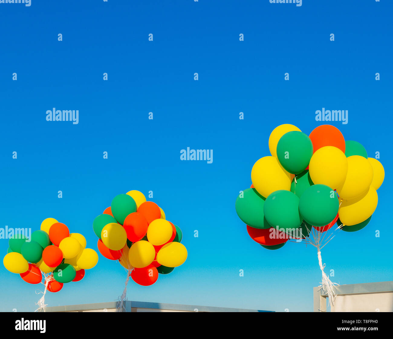 Colourful helium balloons against a blue sky background with copy space ...