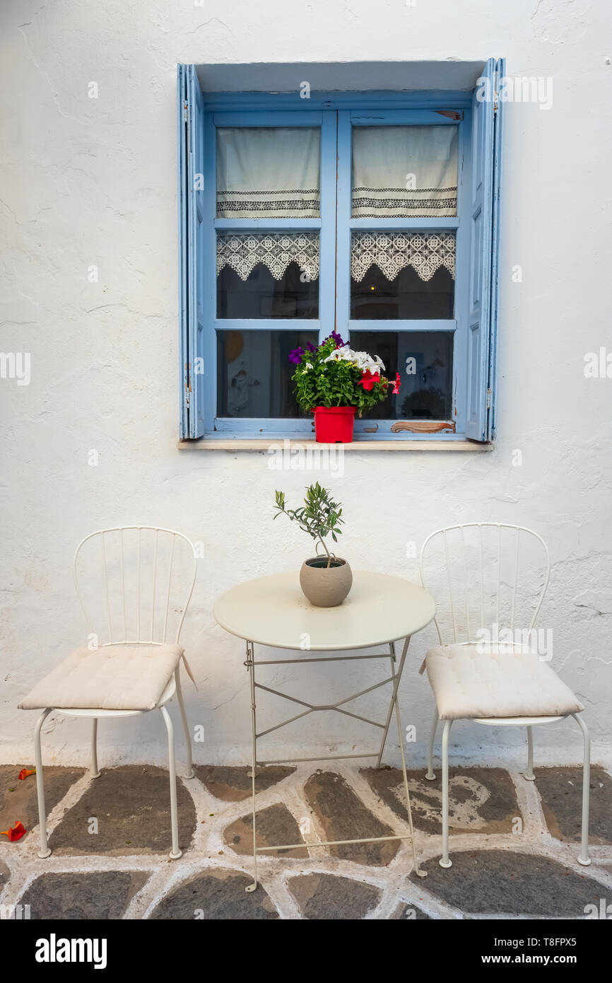 White house facade with blue window, table and chairs in Naoussa town ...