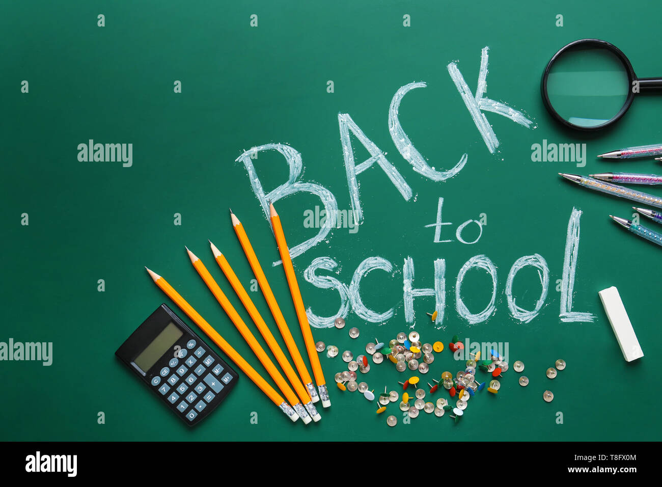 Stationery, magnifying glass and words BACK TO SCHOOL on chalkboard ...