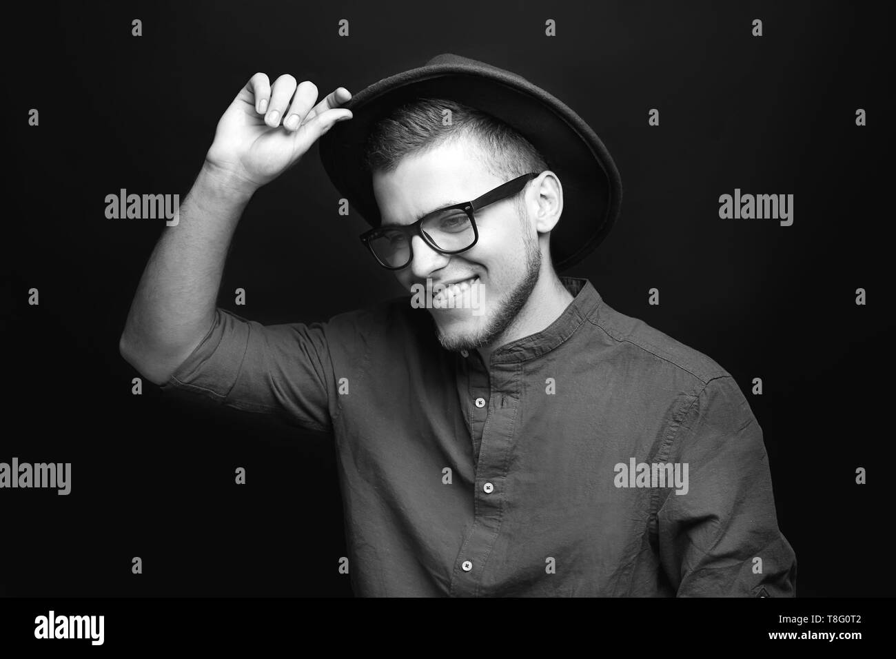 Handsome young man in stylish hat on dark background, black and white ...