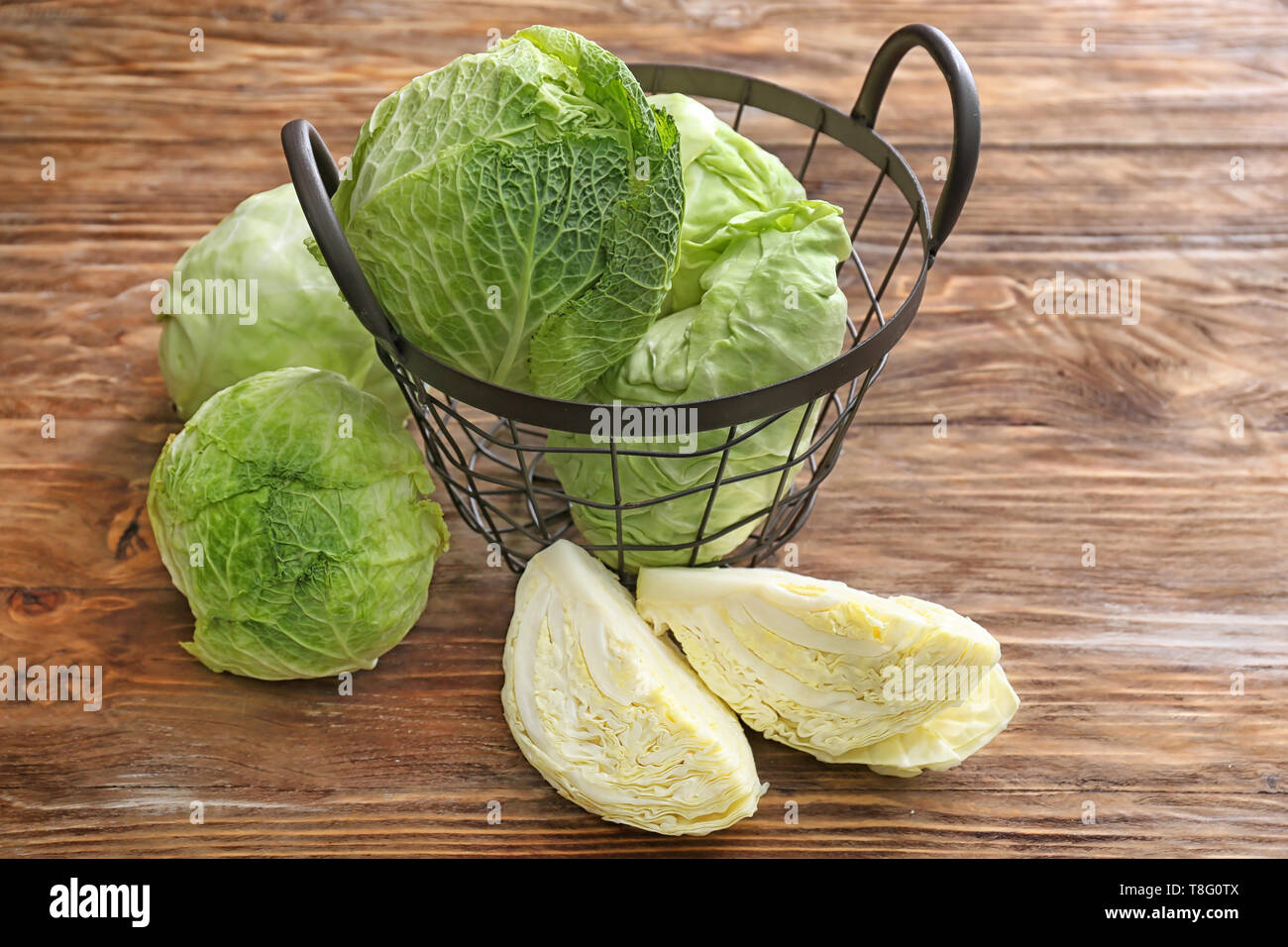 Metal basket with fresh cabbage on wooden table Stock Photo - Alamy