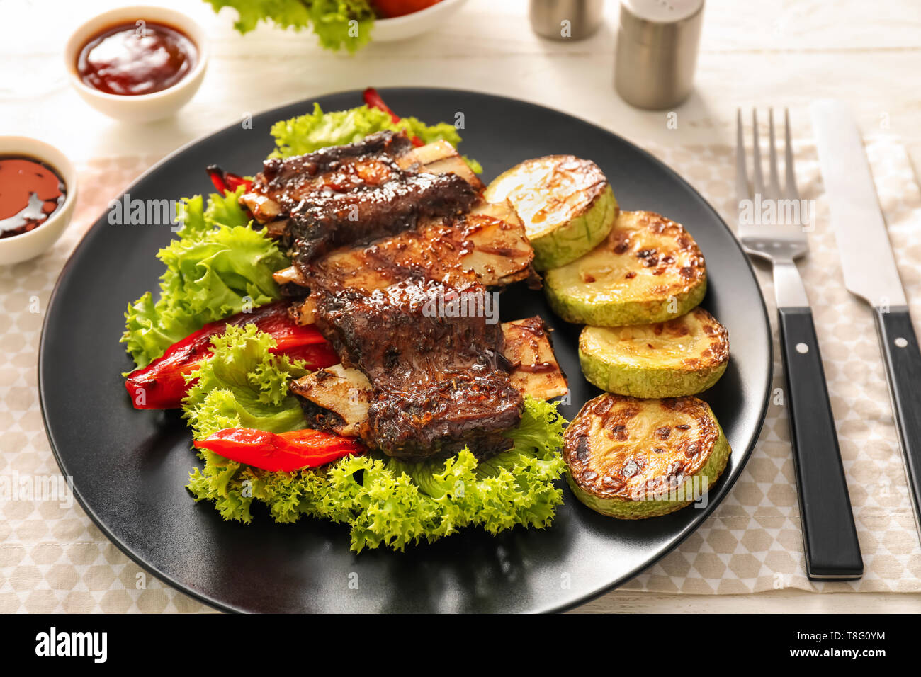 Delicious grilled ribs with vegetables on plate Stock Photo - Alamy