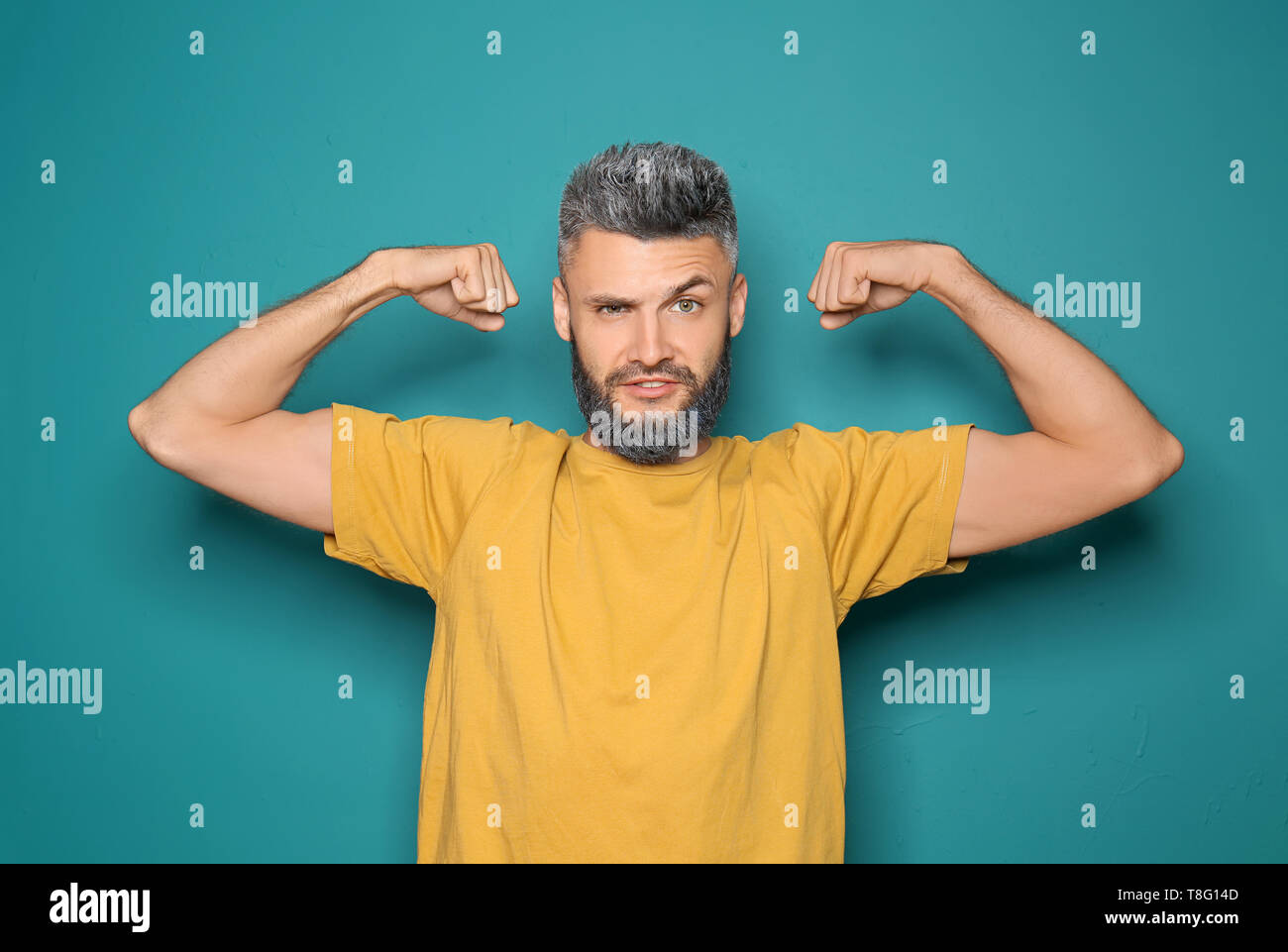 Portrait of emotional man showing muscles on color background Stock ...