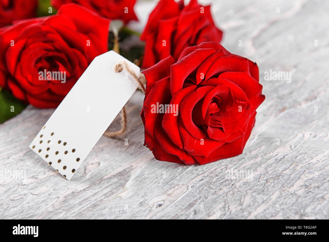 Beautiful bouquet of red roses and tag on light background Stock Photo ...