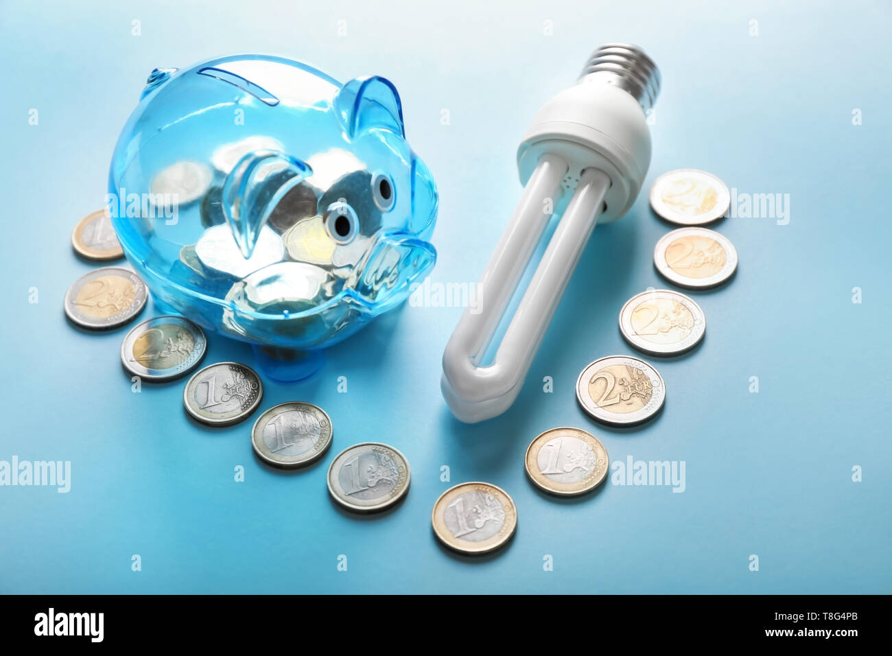 Piggy bank with coins and light bulb on color background. Electricity ...