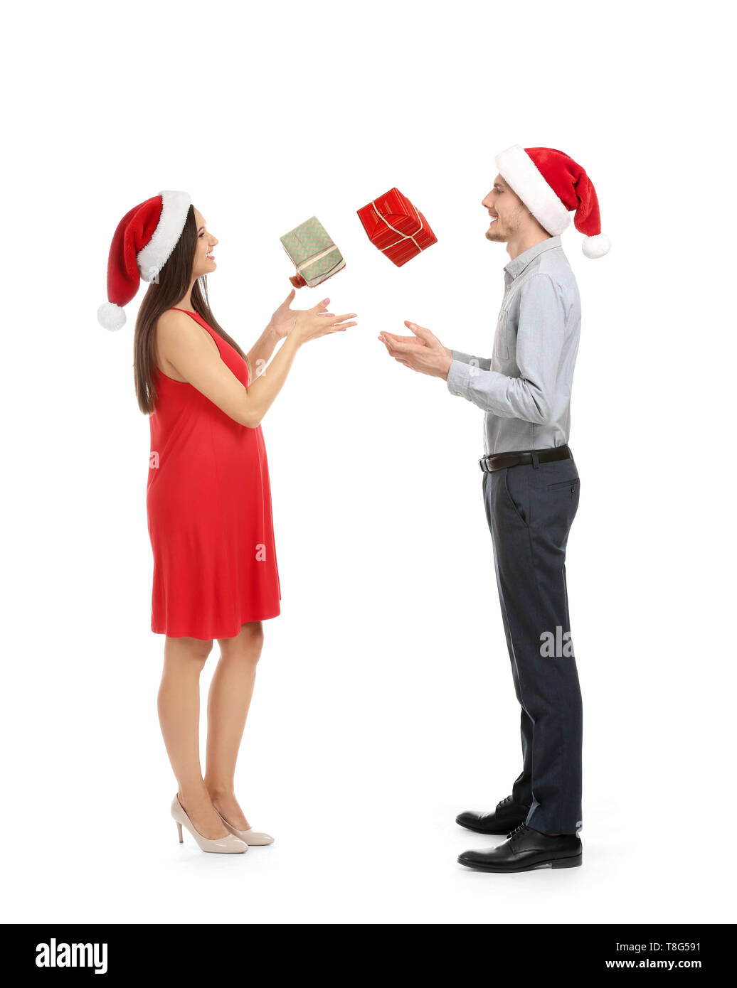 Portrait of cute young couple catching falling Christmas gifts on white ...