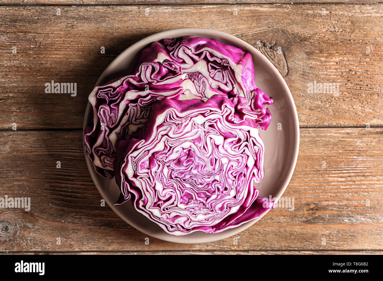 Plate with cut red cabbage on wooden table Stock Photo - Alamy