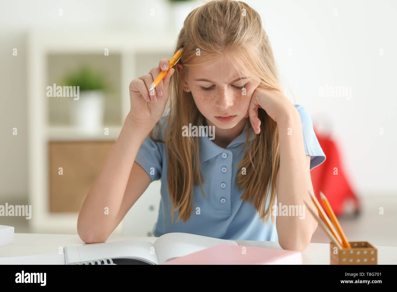 Cute schoolgirl doing homework in classroom Stock Photo - Alamy