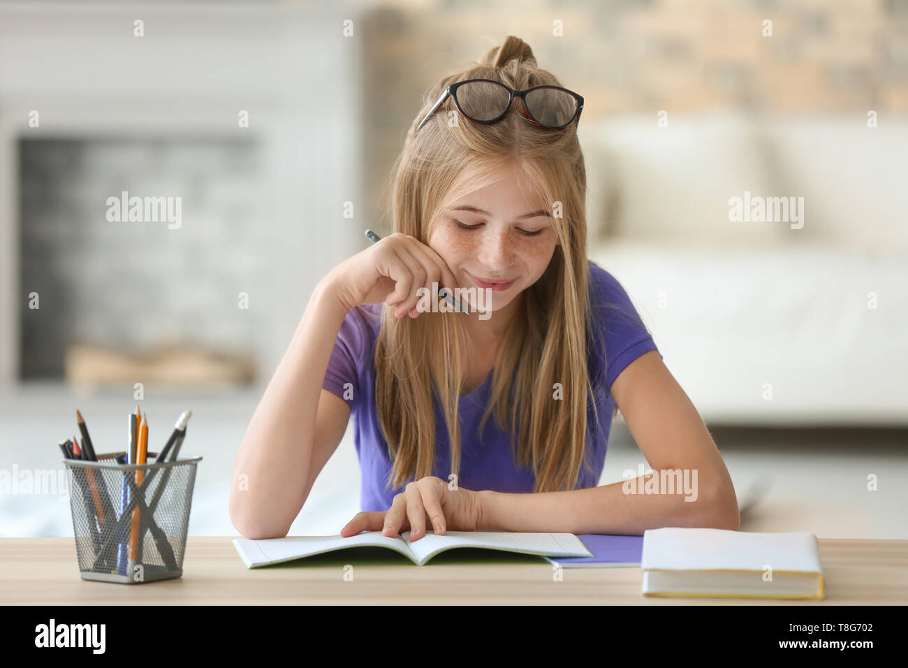 Cute schoolgirl doing homework indoors Stock Photo - Alamy