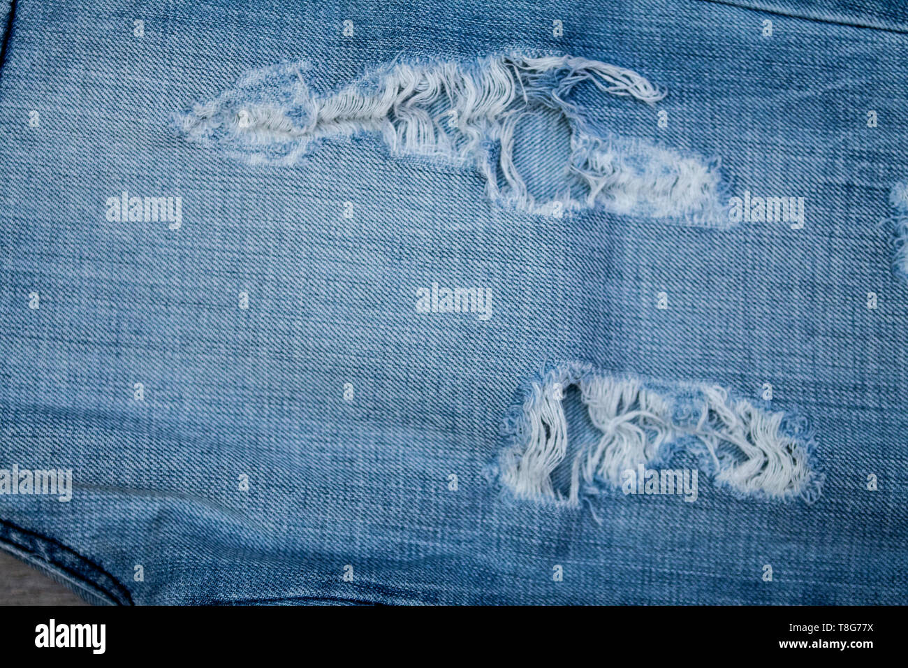 Jean texture with a hole and threads Stock Photo - Alamy