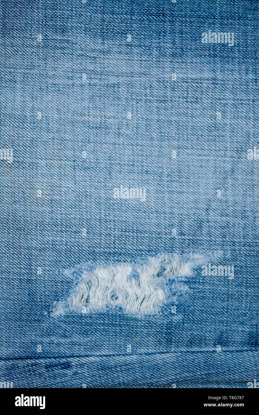 Jean texture with a hole and threads Stock Photo - Alamy