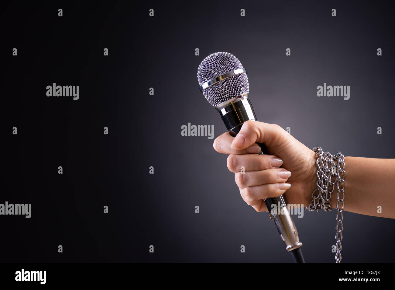 Woman Hand With Microphone Tied With A Chain Depicting The Idea Of