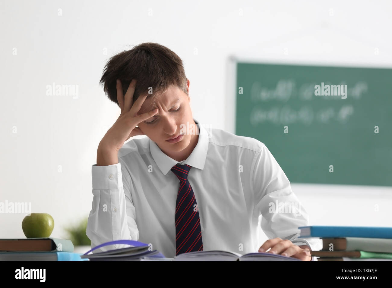 Tired teenage boy at lesson in classroom Stock Photo - Alamy
