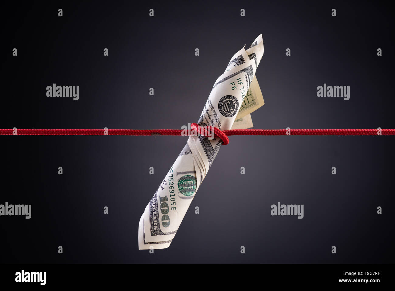 American dollar tied up in red rope knot on dark background with copy ...