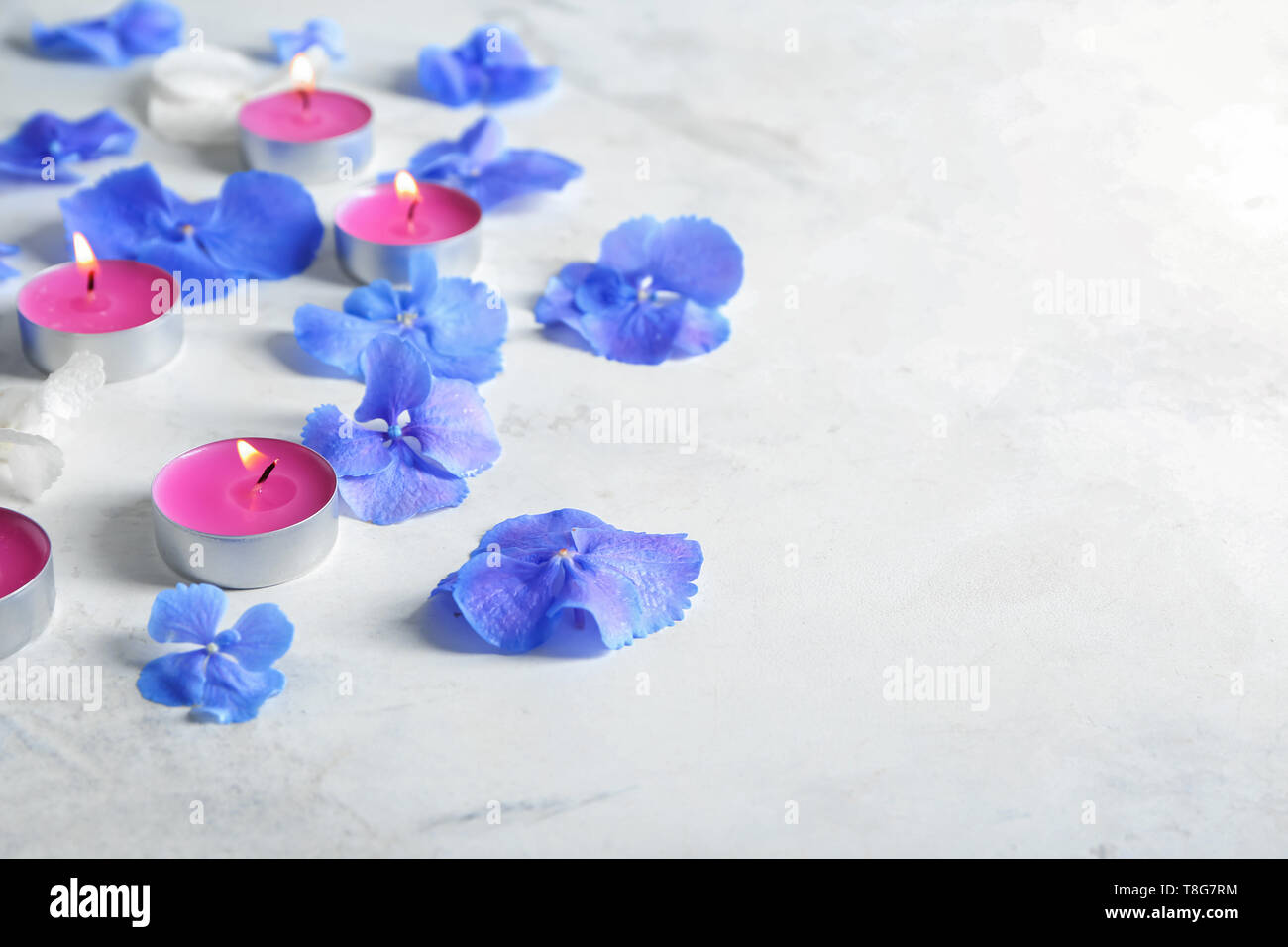 Burning candles with hydrangea flowers on light table Stock Photo - Alamy