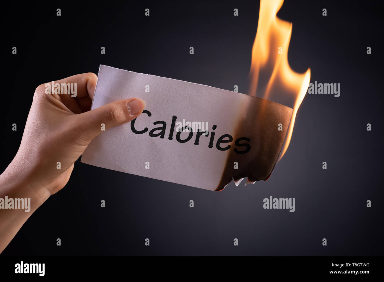 Woman hand holding a burning piece of paper with the word calories ...