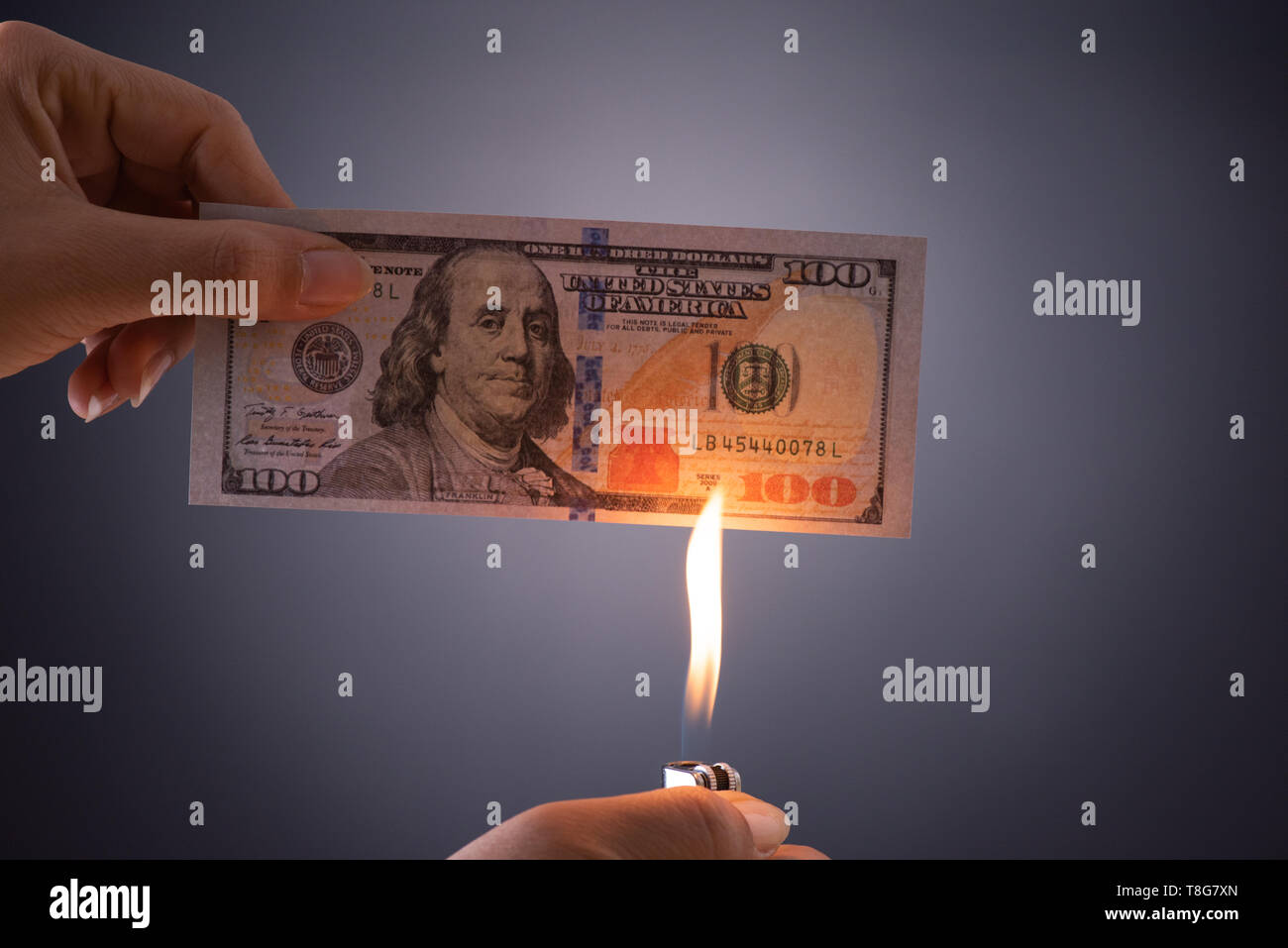 Woman hand holding burning burning dollar cash money over black ...