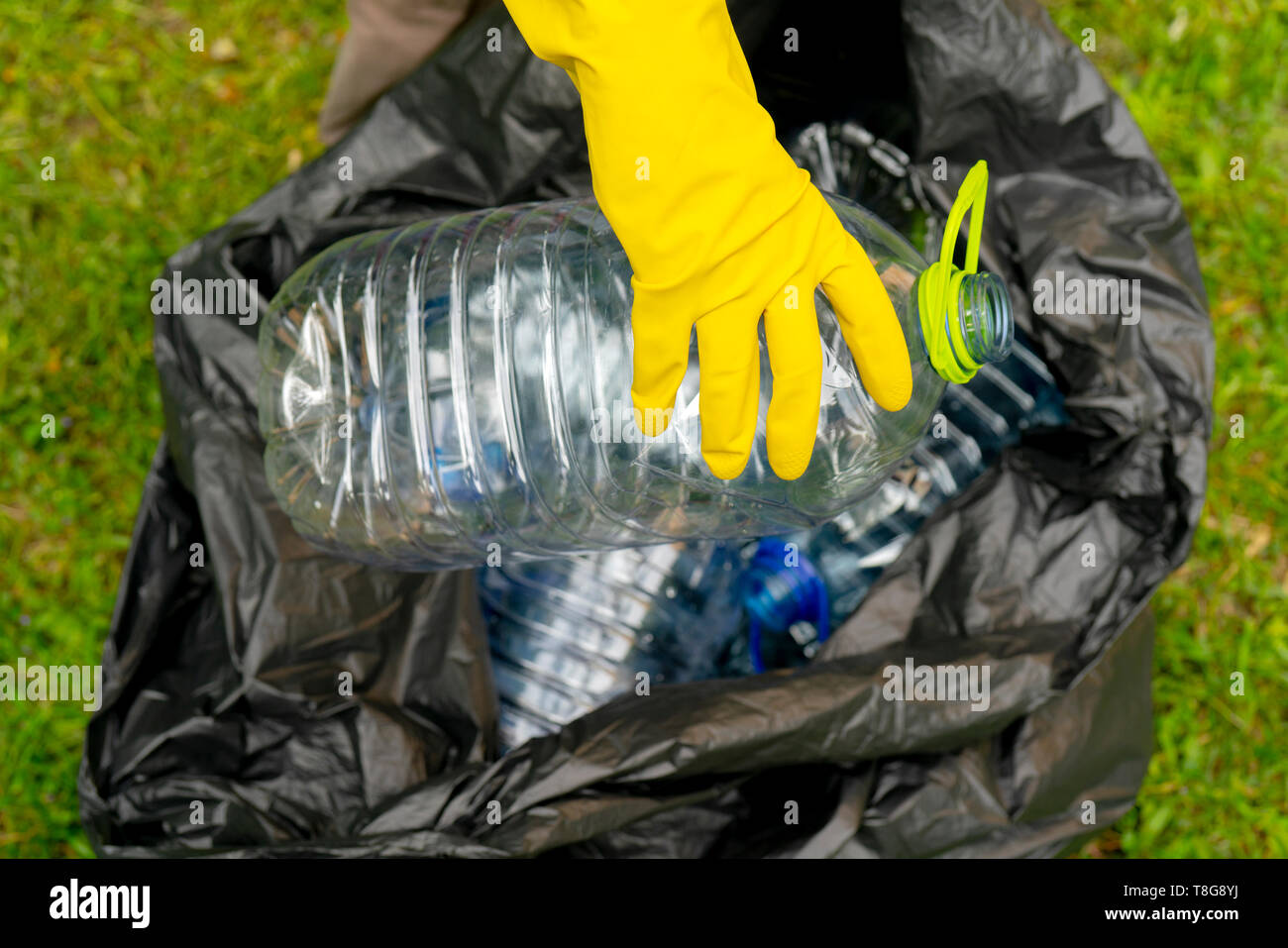 Hand putting empty plastic bottle into a black plastic trash bag Stock ...
