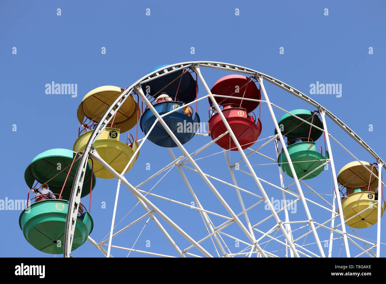 Ferris wheel with colourful cabins on clear blue sky background. People ...