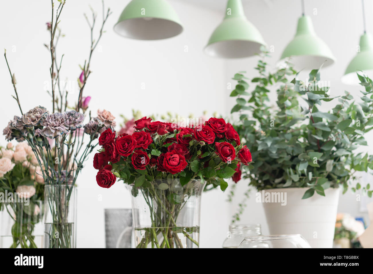 flower shop concept. Vases with different flowers on wooden table ...