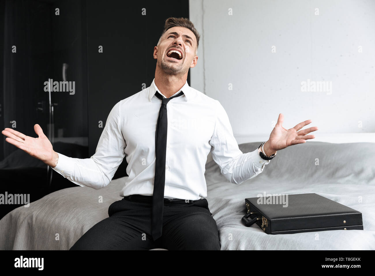 Image of a screaming emotional business man in bedroom indoors at home ...
