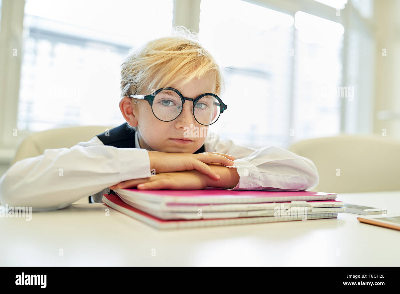 Boy as a student with stack of exercise books does his homework for the ...