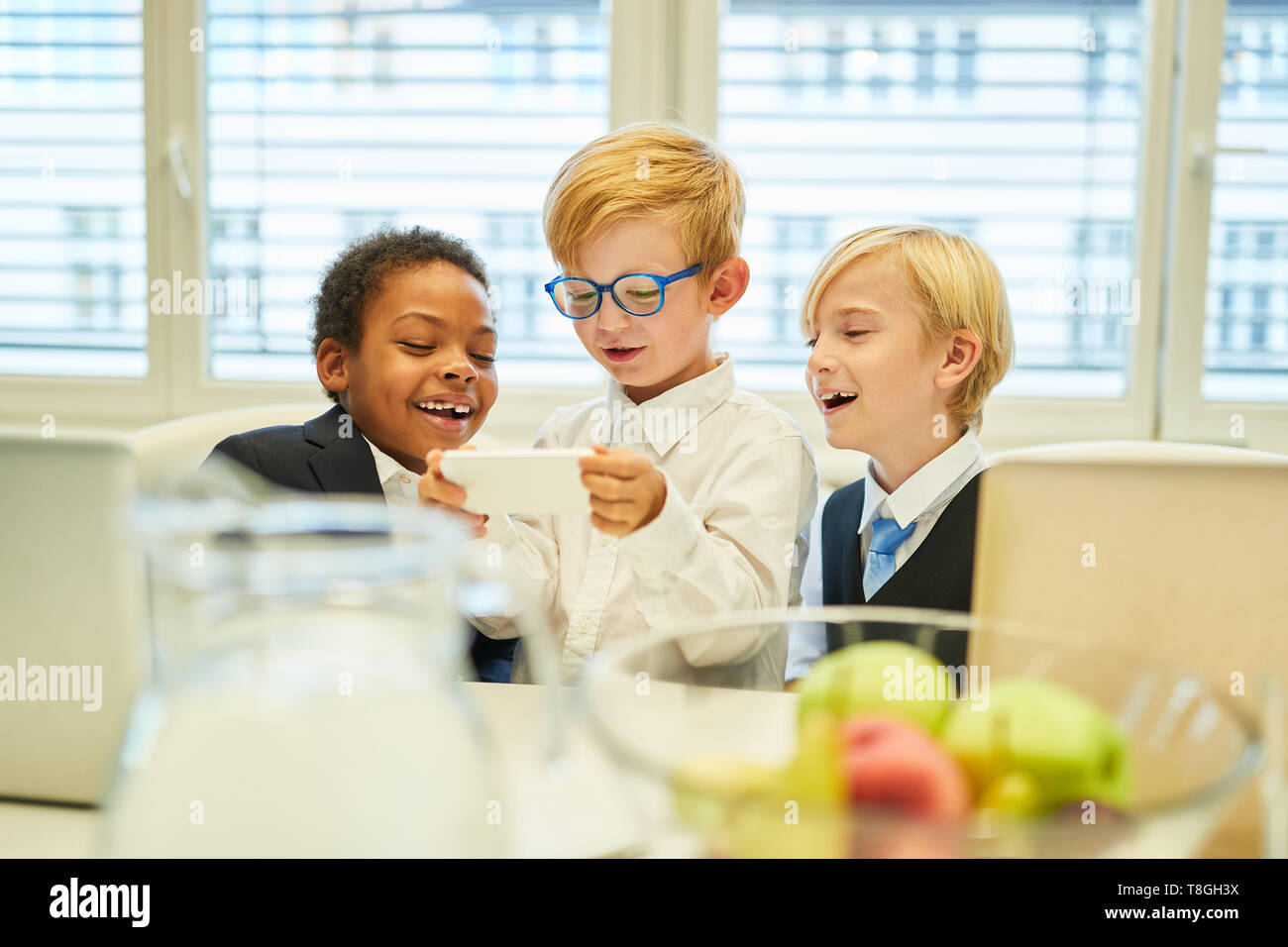 Three boys watch a video together on a smartphone Stock Photo - Alamy