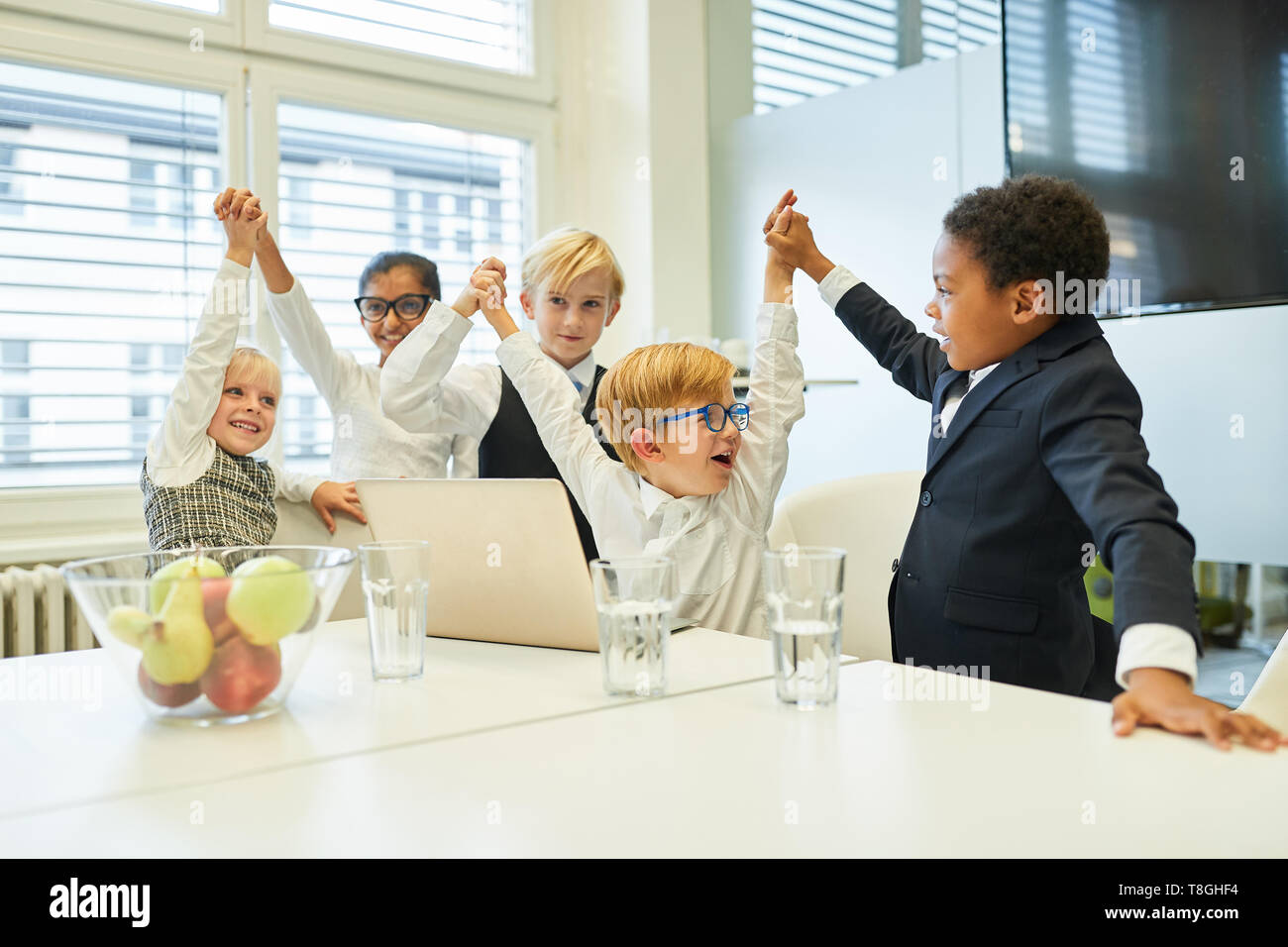 Multicultural group of children as a successful business team cheering ...