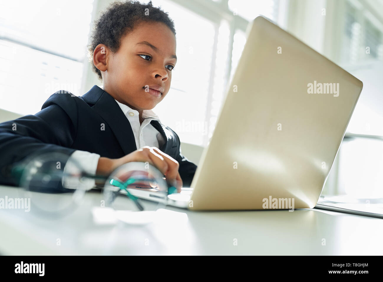 African child as manager works on laptop computer in business start-up ...