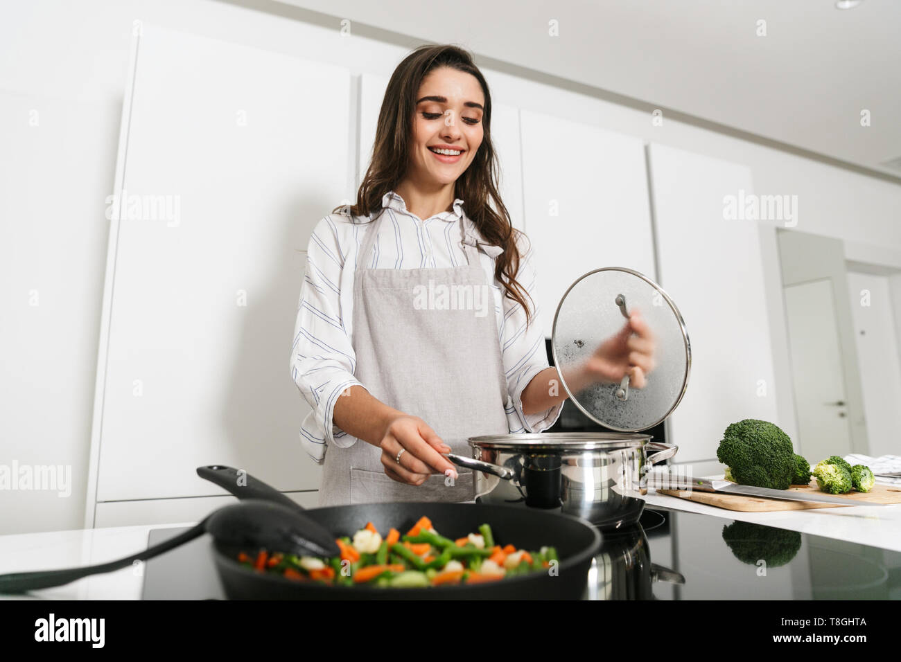 Beautiful young woman cooking healthy dinner at the kitchen, using ...
