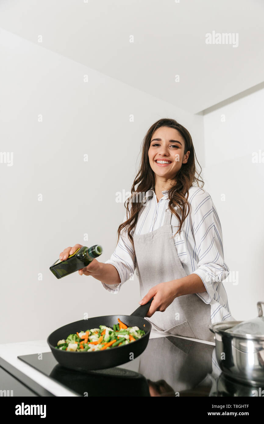 Beautiful young woman cooking healthy dinner at the kitchen, using frying pan Stock Photo - Alamy