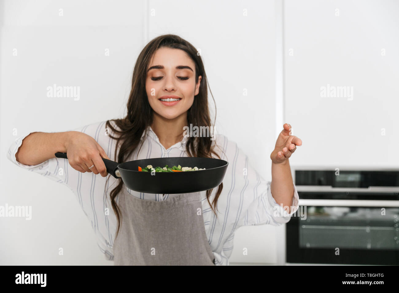 Beautiful young woman cooking healthy dinner at the kitchen, using ...