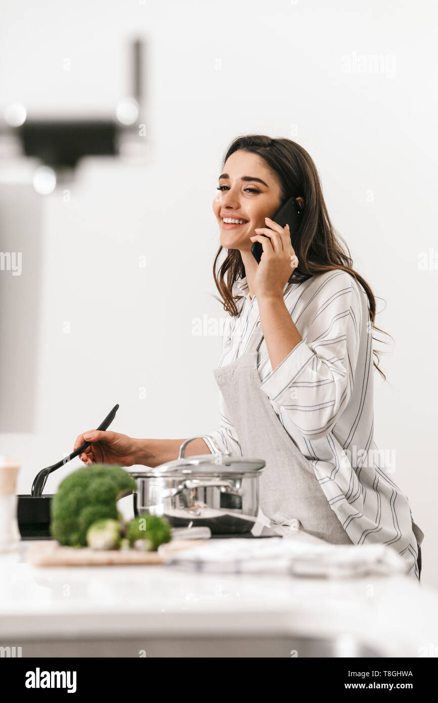 Beautiful young woman cooking healthy dinner in a pot at the kitchen ...