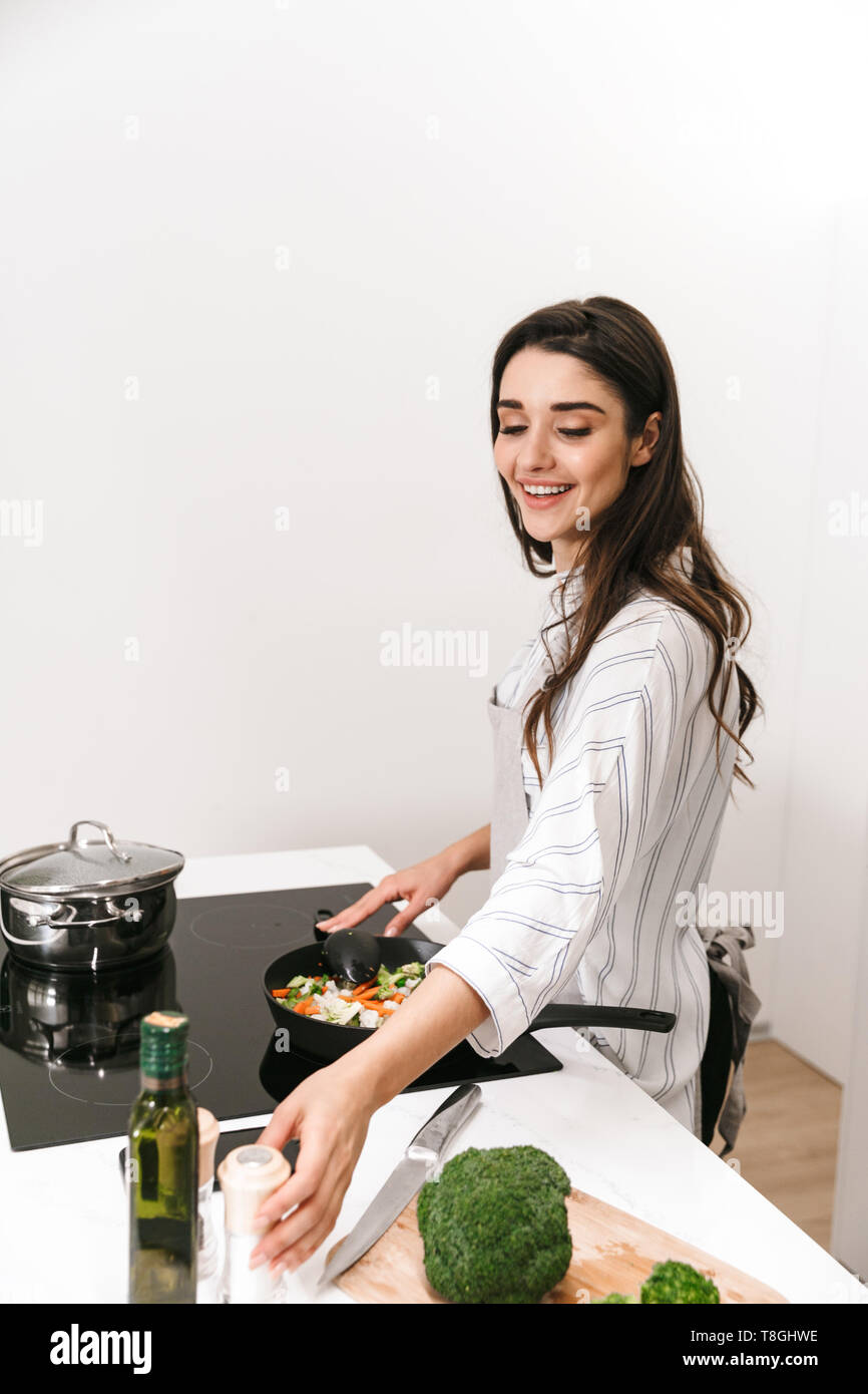 Beautiful young woman cooking healthy dinner at the kitchen, using frying pan Stock Photo - Alamy