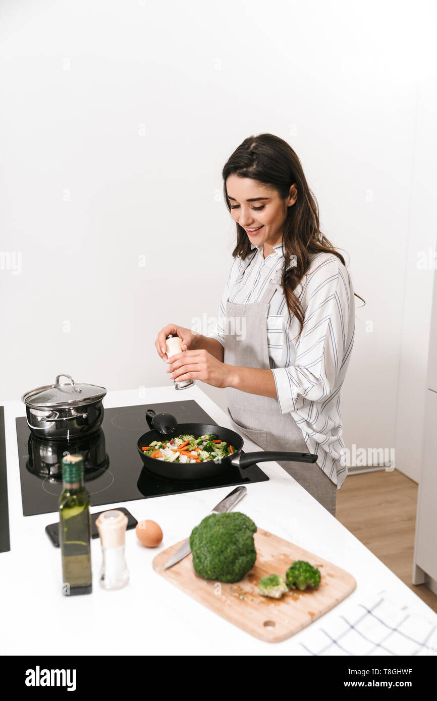 Beautiful young woman cooking healthy dinner at the kitchen, using frying pan Stock Photo - Alamy