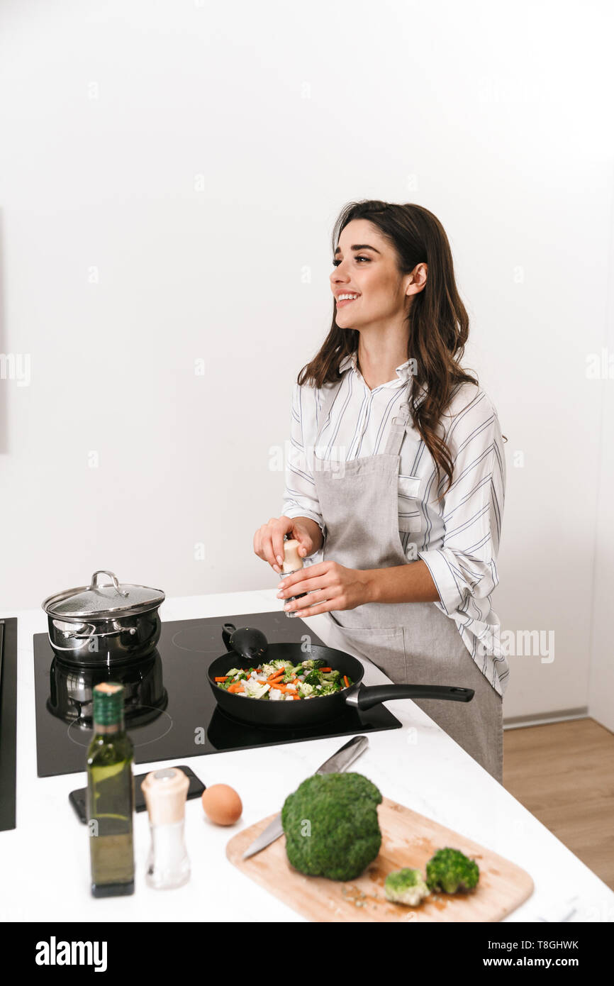 Beautiful young woman cooking healthy dinner at the kitchen, using frying pan Stock Photo - Alamy