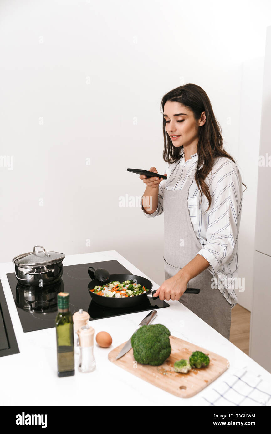 Beautiful young woman cooking healthy dinner at the kitchen, using ...