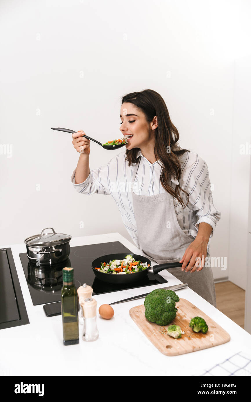 Beautiful young woman cooking healthy dinner at the kitchen Stock Photo ...