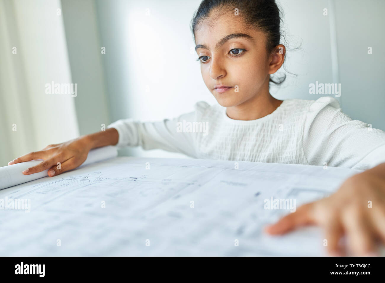 Girl as architect and project developer looks at a construction drawing ...