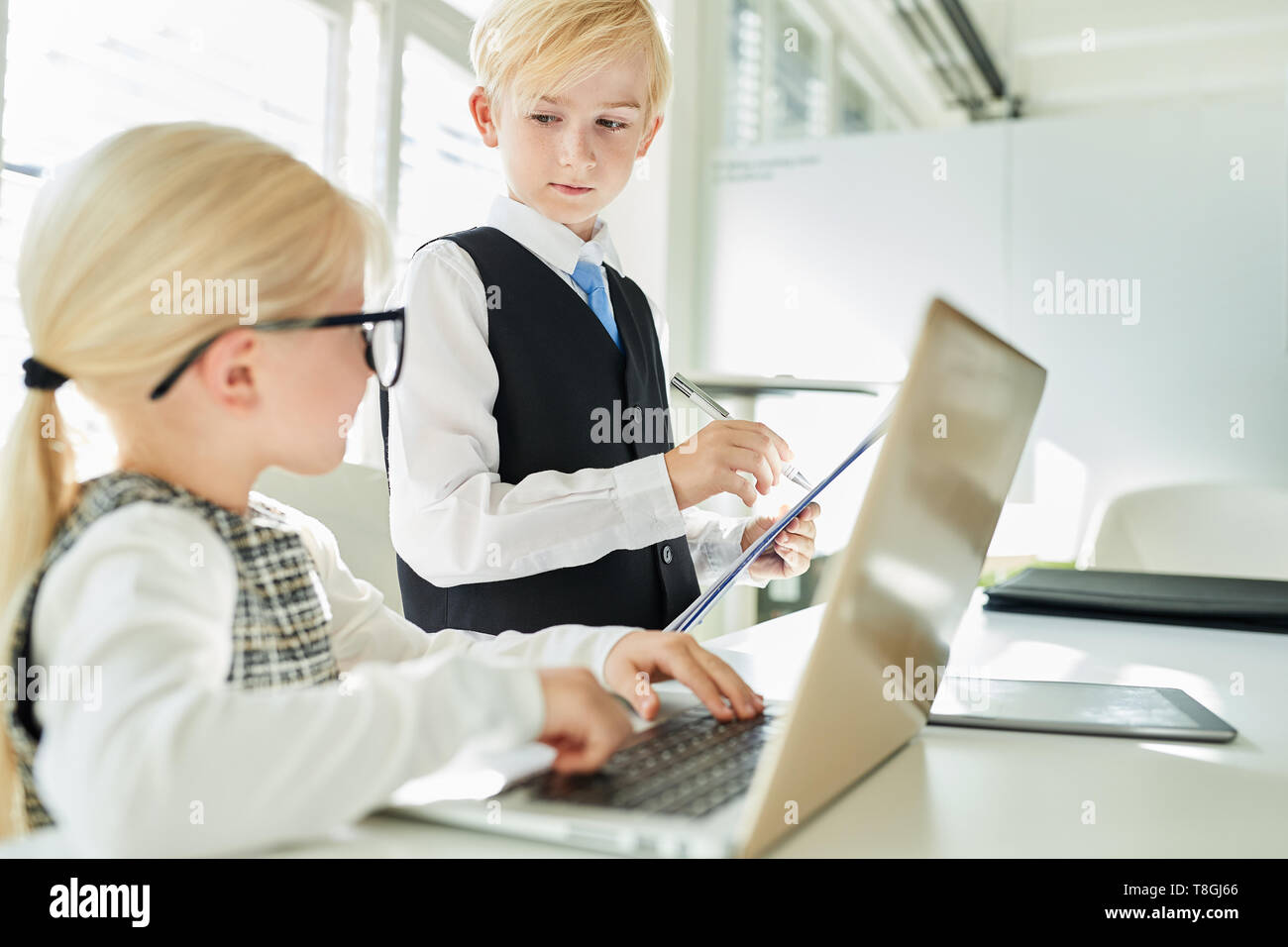 Boy and girl at laptop computer as a team in start-up business office ...