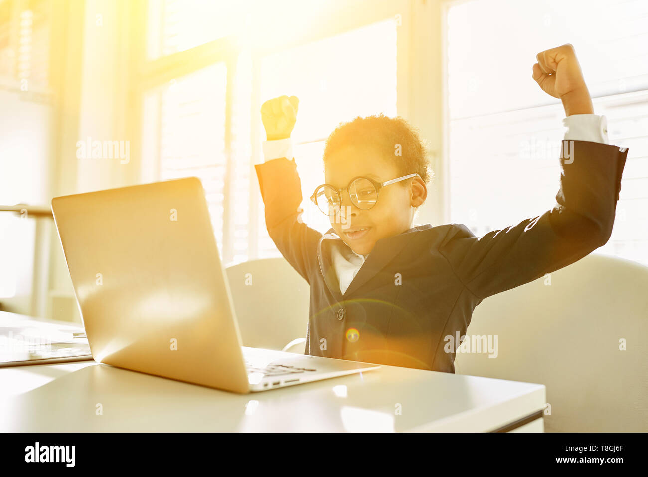 Cheering african kid as a business manager in front of laptop computer ...