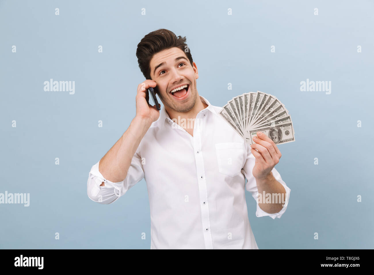 Portrait of a cheerful handsome young man standing isolated over blue ...