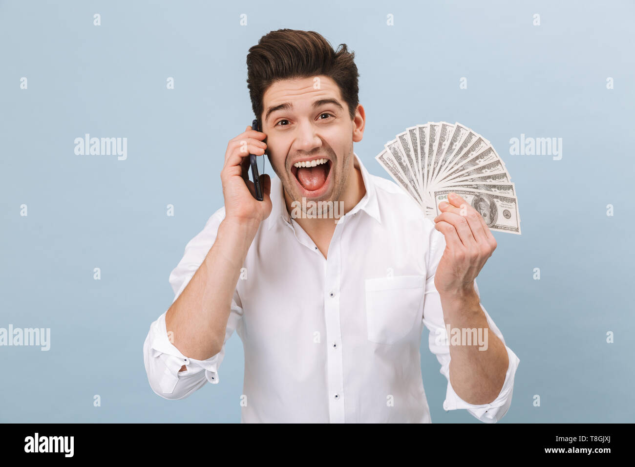 Portrait of a cheerful handsome young man standing isolated over blue ...