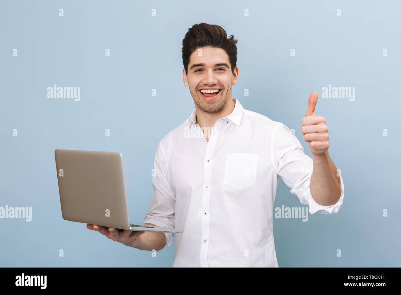 Portrait of a cheerful handsome young man standing isolated over blue ...