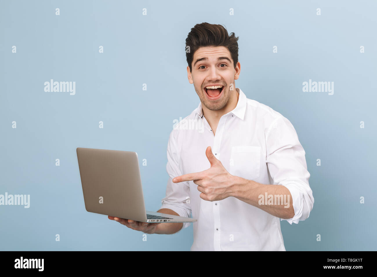 Portrait of a cheerful handsome young man standing isolated over blue ...