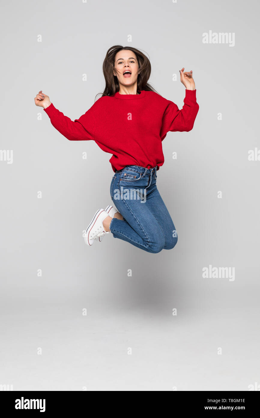 Full length portrait of a laughing woman jumping over gray background ...