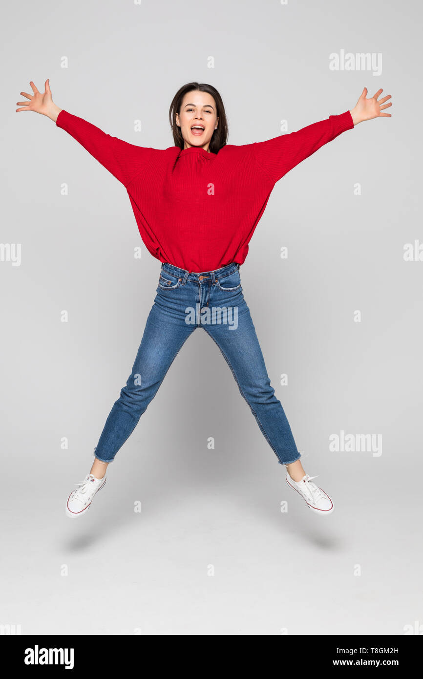 Full length portrait of a laughing woman jumping over gray background ...